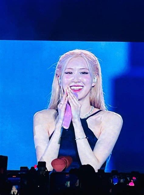 A Woman Standing In Front Of A Crowd Holding Her Hands To Her Face And