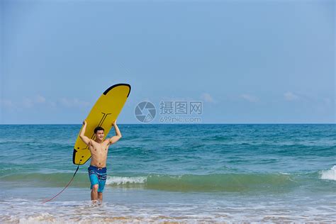 年轻男士举着冲浪板走向岸边高清图片下载 正版图片501743409 摄图网