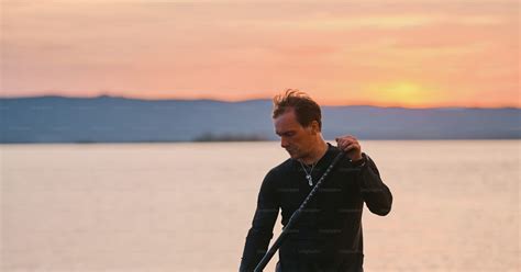 조용한 물에서 나무 판자 위에 서서 노를 젓고 있는 남자의 전신 사진 경치 좋은 산 전망과 함께 일몰에 서핑 사진 Unsplash의 러시아 이미지