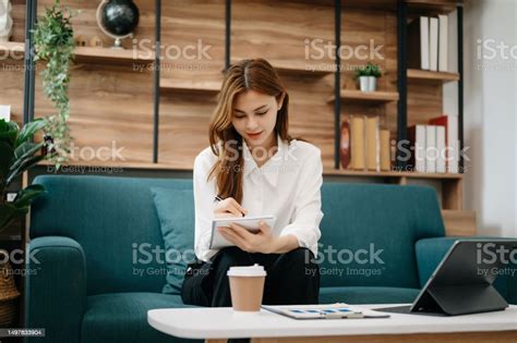 자신감 넘치는 아시아 여성이 홈 오피스에서 메모장과 태블릿을 들고 미소를 지으며 서 있다 18 19세에 대한 스톡 사진 및 기타 이미지 18 19세 가상현실 거실