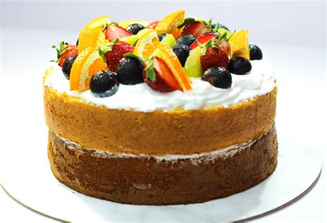 수제 Tres Leches 케이크는 머랭 프로스팅과 신선한 포도 키위 딸기 및 오렌지를 흰색 접시에 곁들입니다 흰색으로 분리 된