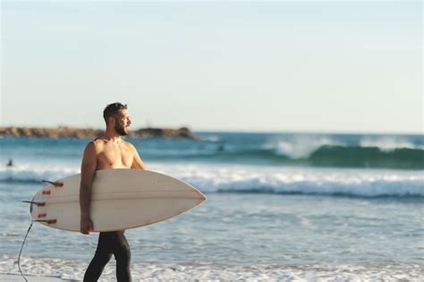 Premium Photo A Smiling Athletic Man Surfer With Naked Torso Walking