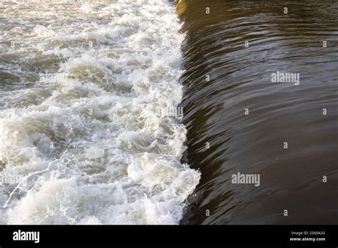 clean water flowing into polluted river creating foam waves and a
