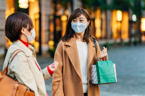 쇼핑백을 들고 거리에서 걷고 질병 예방을 위한 보호얼굴 마스크로 얼굴을 가리는 두 여성 2명에 대한 스톡 사진 및 기타 이미지