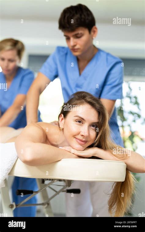 Relaxed Young Woman Having Body Massage Therapy Conducted By Two