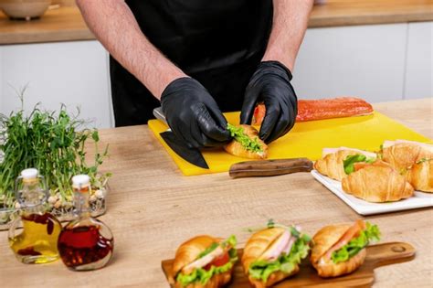 Premium Photo A Chef In Black Gloves Prepares A Croissant Sandwich On