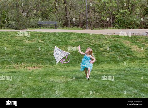 Young Caucasian Girl Laughing As She Runs Trying To Fly Kite Stock