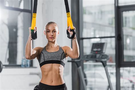 매력적인 운동 Sportswoman 정지 스트랩 체육관에서 운동을 하 고 카메라를 보고 근육질 체격에 대한 스톡 사진 및 기타