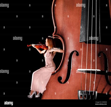 Tiny Female Violinist Playing A Violin Sitting On The Edge Of The Big