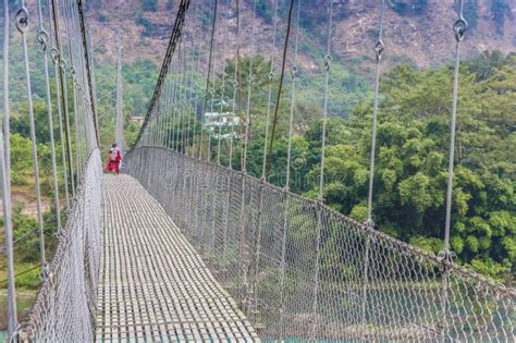 Women Crossing Suspension Bridge Over The Trishuli River In Nepal Stock