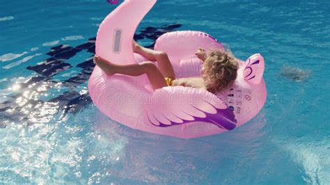 Happy Cute Boy Is Sitting On Inflatable Flamingo With Mother In