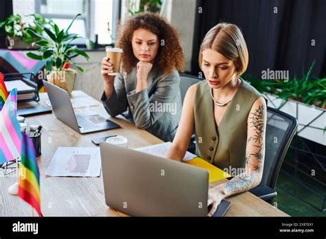 In A Lively Workspace Two Colleagues Engage In A Focused Discussion