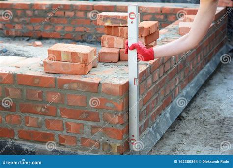 Bricklayer Using A Spirit Level To Check Bricklaying Wall Outdoors