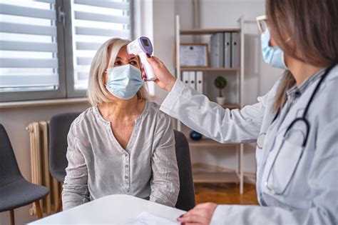병원에서 적외선 온도계로 환자의 체온을 확인하는 젊은 의사 2명에 대한 스톡 사진 및 기타 이미지 2명 35 39세 60