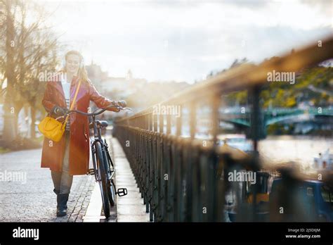 Modern 40 Years Old Woman In Red Rain Coat With Bicycle Walking Outside