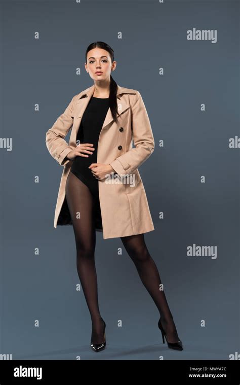 Slim Woman In Black Pantyhose And Beige Trench On Dark Background Stock