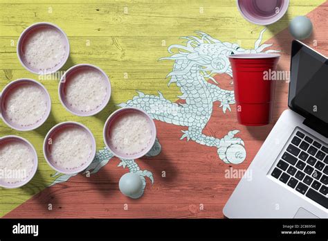 Bhutan Flag Concept With Plastic Beer Pong Cups And Laptop On National