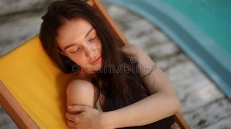 Slow Motion A Girl With Long Hair In A Black Swimsuit Sunbathes While Lying On A Beach Chair On