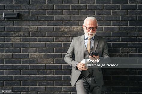 한 노인 사업가가 야외에 서서 스마트폰과 커피를 들고 있습니다 70 79세에 대한 스톡 사진 및 기타 이미지 70 79세