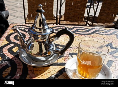Reich verzierte marokkanische Teekanne und Glas auf einem Mosaik Tisch in einem Straßencafé in