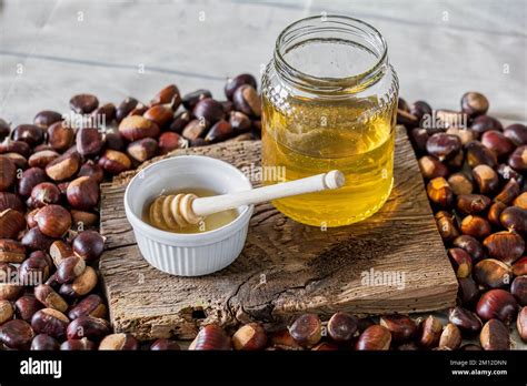 Jar Of Bee Honey With Small Cup And Honey Dipper On Antique Wooden