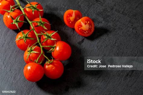 물 방울 생 전체 및 반으로 된 아름다운 신선한 포도 나무 토마토 검은 색 질감 슬레이트 배경에 지중해 식단의 성분 복사 공간이 있는 상단 뷰입니다 0명에 대한 스톡 사진