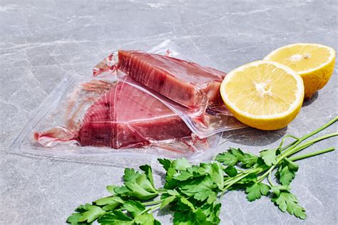 회색 대리석 배경에 진공 패키지에 붉은 참치 필렛 신선한 생선 레몬 파슬리요리 재료 건강한 식습관의 개념 단백질 물고기에 대한