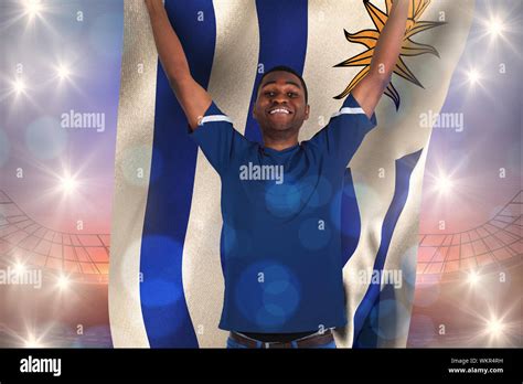 Cheering Football Fan In Blue Jersey Holding Uruguay Flag Against Large