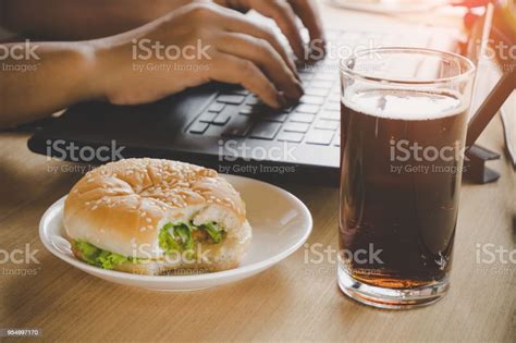 컴퓨터 노트북에서 작업 하는 동안 정크 푸드 햄버거와 차가운 음료를 먹는 여자 건강관리와 의술에 대한 스톡 사진 및 기타 이미지