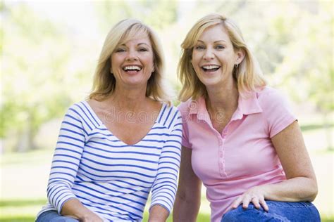 Twee Vrouwen Die In Openlucht Het Glimlachen Zitten Stock Foto Image