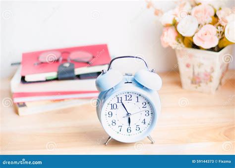 Light Blue Alarm Clock On Wooden Table With Books And Glasses Stock