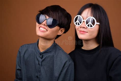 Young Asian Lesbian Couple Together And In Love Against Brown Ba Stock