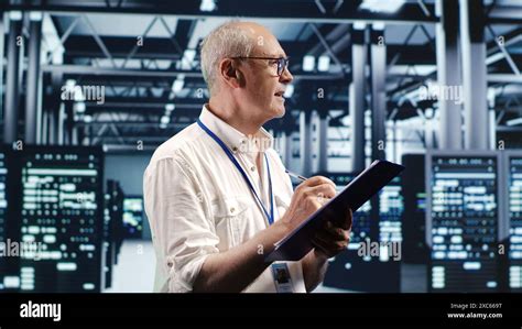 Elderly Engineer Looking Around High Tech Data Center Using Clipboard