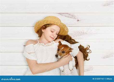 Маленькая девочка обнимает ее собаку лежащую на полу Стоковое