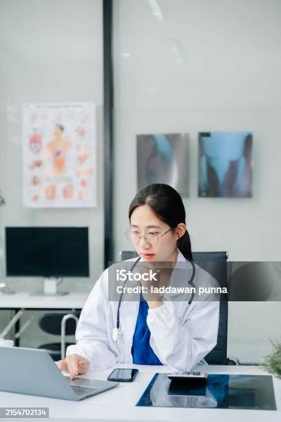 아름다운 의사 의사가 사무실 병원의 테이블에 앉아 있습니다 매력적인 치료사 여성 시술사 약사 웃는 얼굴로 정제를 사용 20 24