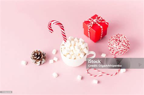 마시멜로 캔디 지팡이 빨간 선물 상자 소나무 콘 분홍색 배경에 장식용 레이스가있는 화이트 머그잔 플랫 레이 겨울 전통 음료 음식 축제 장식 크리스마스 새해는 크리스마스