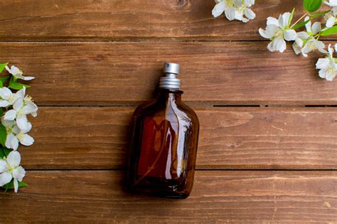 향수 에센셜 오일 어두운 유리 항아리 천연 화장품 천연 향수 꽃 배경 플랫 레이 향기로운 물이 있는 병 나무 배경에 건강한 천연 화장품의 개념 꽃 나무에 대한 스톡 사진 및