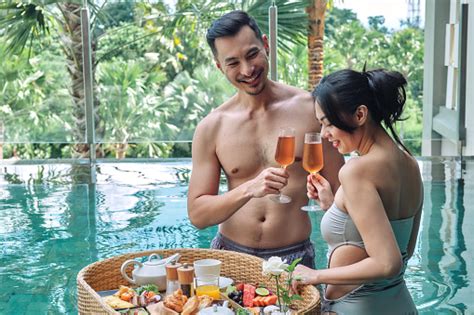 수영장에서 아침 식사를 하는 행복한 아시아 커플 고급 호텔에 떠 있는 아침 식사 트레이 남자와 여자가 샴페인 잔으로 부딪히고 있다 샴페인 와인에 대한 스톡 사진 및 기타