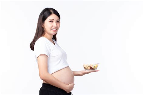 행복한 임신 한 젊은 아시아 어머니는 카피 공간이있는 흰색 배경에 아기와 임산부를위한 과일 건강 식품을 가지고 있습니다 건강한