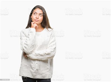 젊은 아름 다운 아랍 여자 손으로 턱 질문 잠겨있는 표현에 대 한 생각에 고립 된 배경 위에 겨울 스웨터를 입고 사려깊은 얼굴