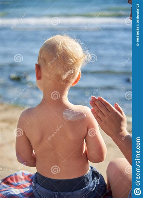 Mom Smears Her Son`s Back With Sunblock Cream On The Sea Beach Stock