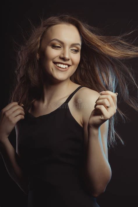 Happy Brunette Model In Black Dress With Curly Hair In Motion Stock
