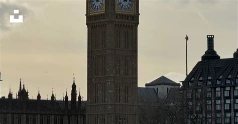 A Tall Clock Tower Towering Over A City Photo Free Clock Tower Image