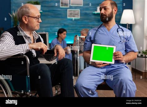 Medical Nurse Holding A Green Screen Tablet With During A Medical