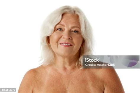 금발 머리를 한 60 대 아름 다운 노인 여성이 어깨를 드러내고 서서 흰색 스튜디오 배경에 미소를 짓고 있습니다 60 64세에