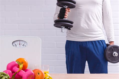 남자는 아령과 전경 체중 규모 과일 야채 및 측정 테이프에서 운동을하고 있습니다 다이어트와 스포츠 개념 건강한 생활방식에 대한