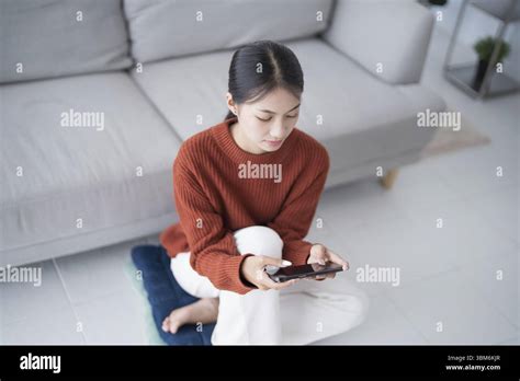 Asian Woman Controlling Smart Home Mobile Phone With Smart Home App In