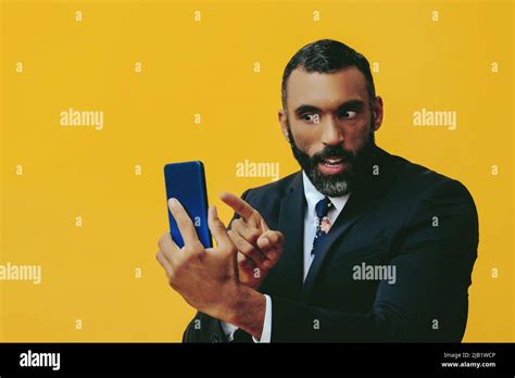 Portrait Of Angry Handsome Bearded Man In Suit And Tie With Smartphone Video Call Pointing