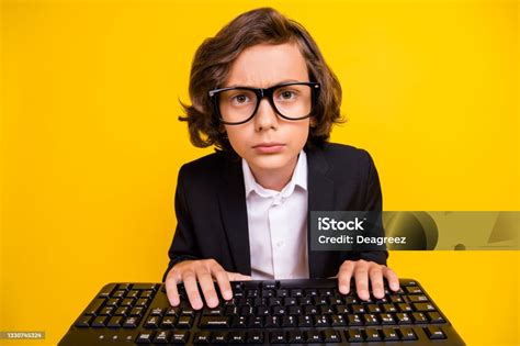 사진 차분한 학습자 소년 타이핑 키보드 룩 웹 카메라 착용 안경 검정 유니폼 고립 된 노란색 색상 배경 갈색 머리에 대한 스톡