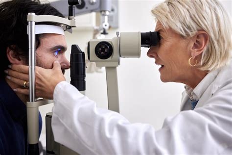 Examen o prueba de la vista del hombre con el paciente y el médico en la consulta de optometría